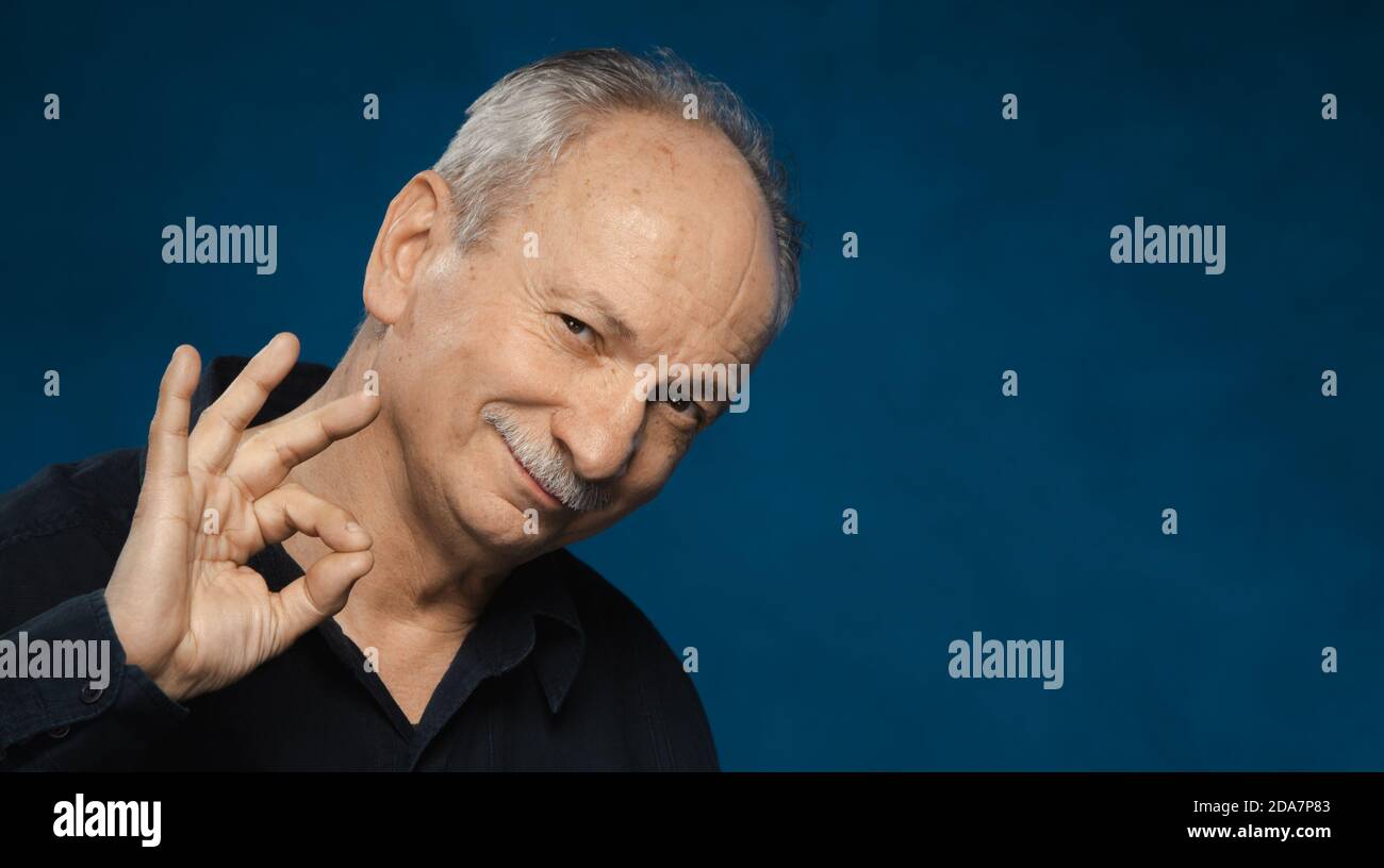 Old macho man. Smiling elderly man shows ok gesture with his hands ...