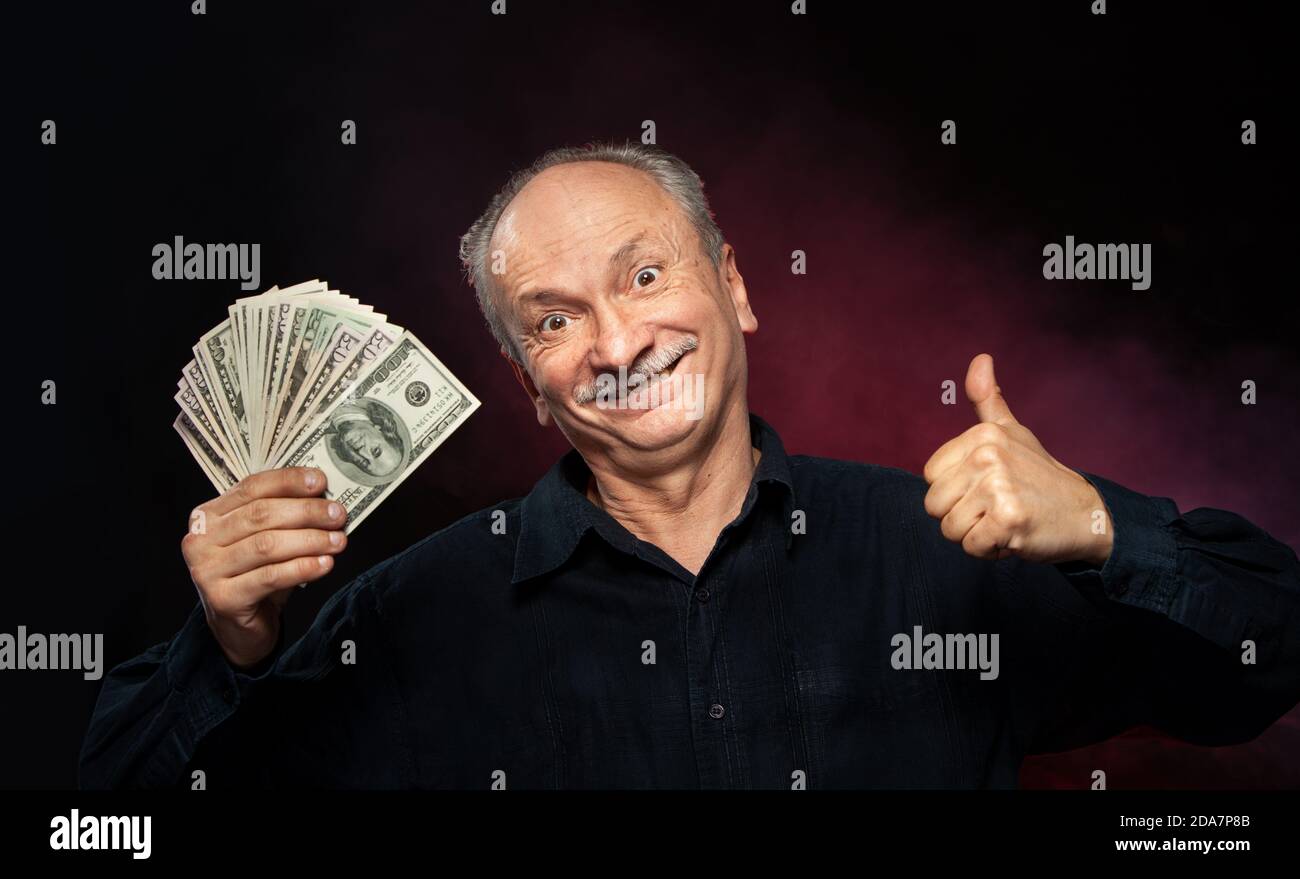 Senior gentleman holding a stack of money. Portrait of an excited old ...