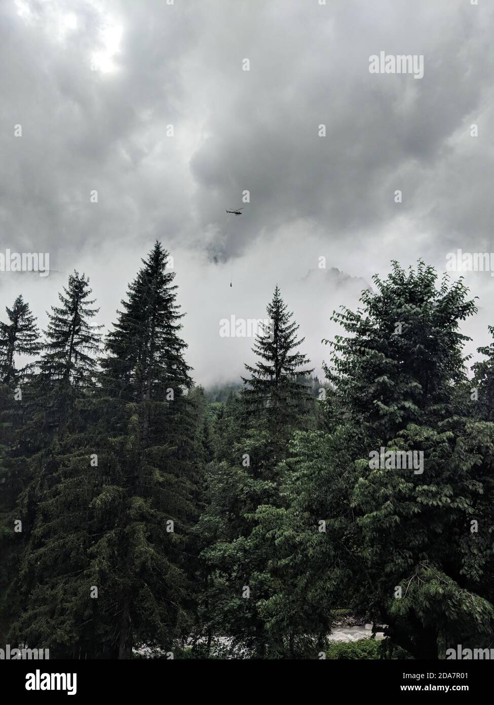 Helicopter carrying goods and flying through the gloomy looking sky ...