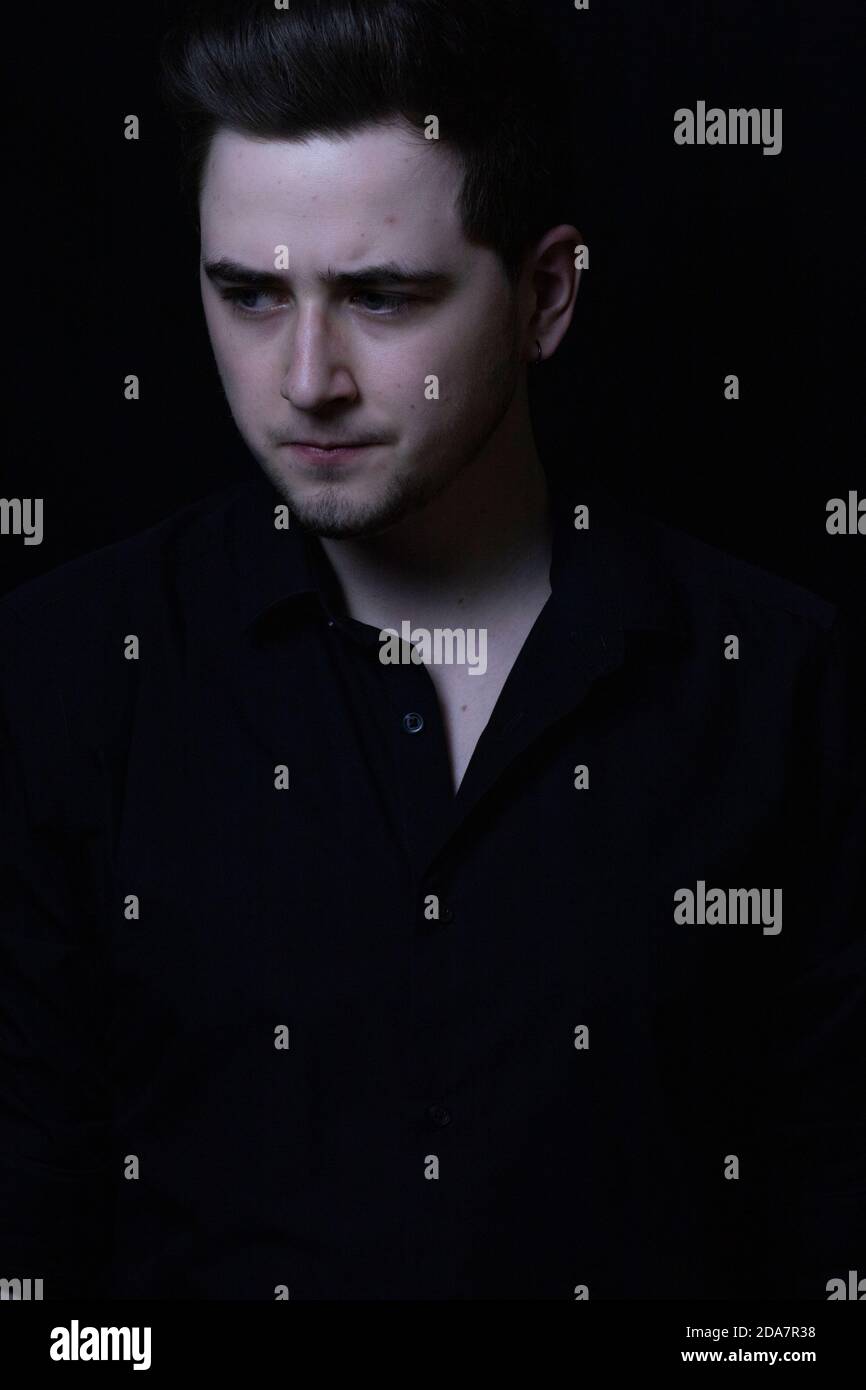 Man in front of black background looking at the ground Stock Photo - Alamy