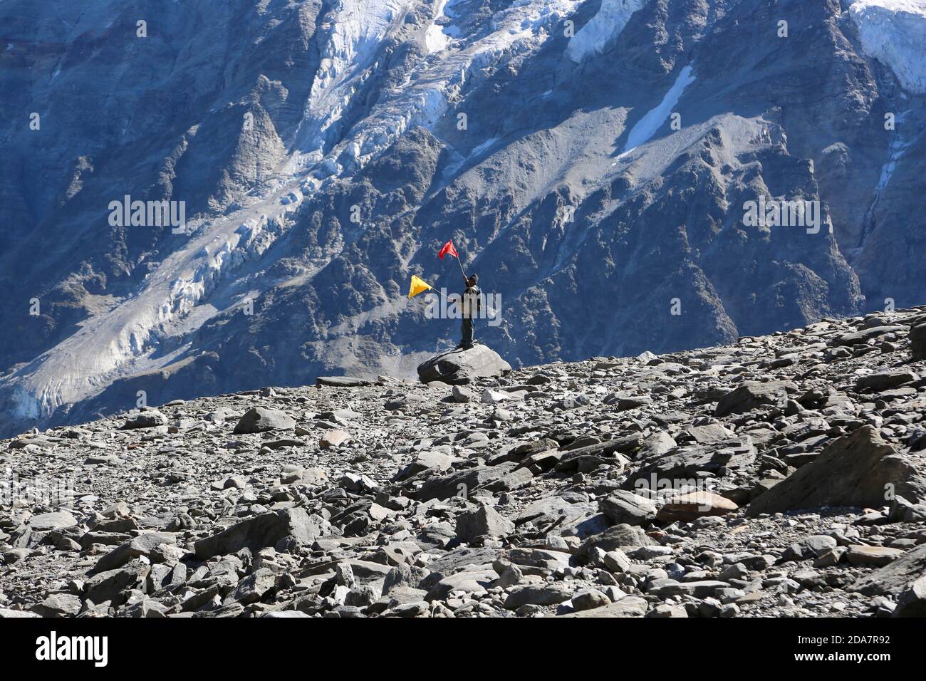 Mountaineer giving signal with flag in upper Himalaya. The Himalayas ...