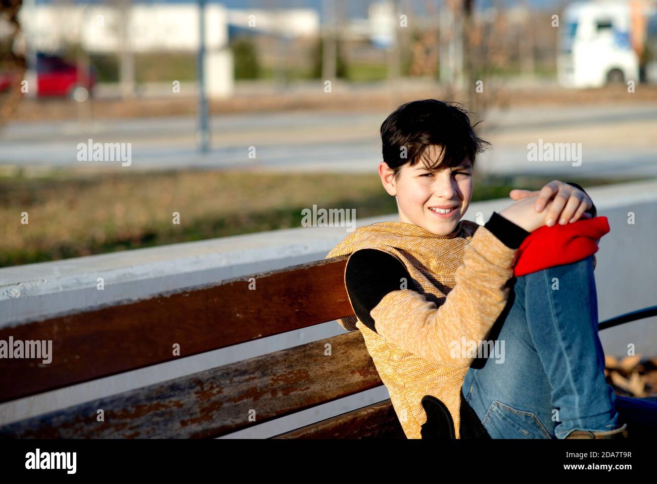 Young boy sitting on a bench while looking at the camera Stock Photo ...