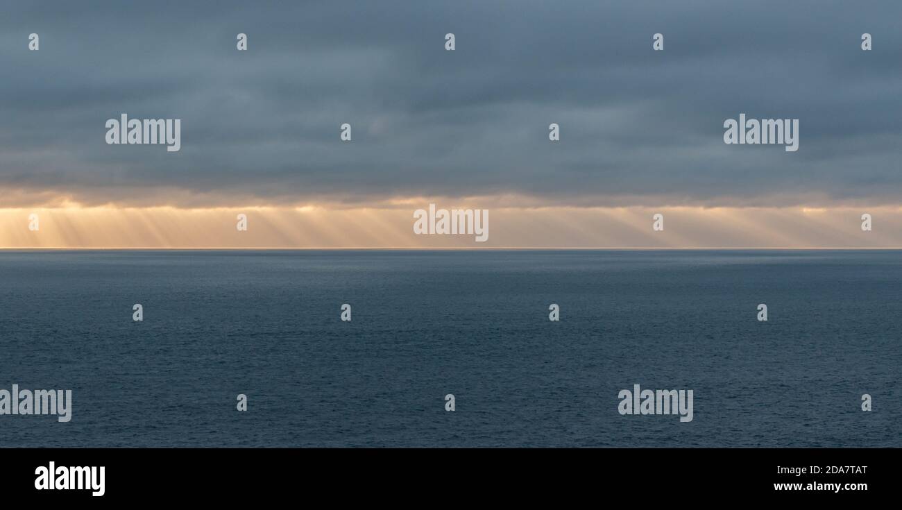 Sun rays coming down from the clouds over the ocean Stock Photo - Alamy