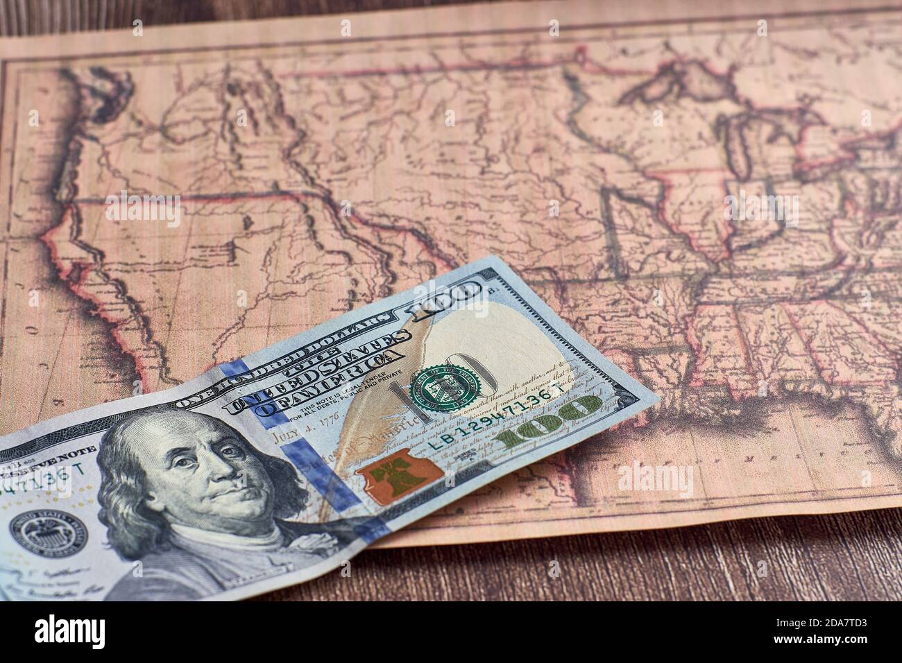 Top view closeup of 100$ banknote placed on an ancient map on a wooden ...