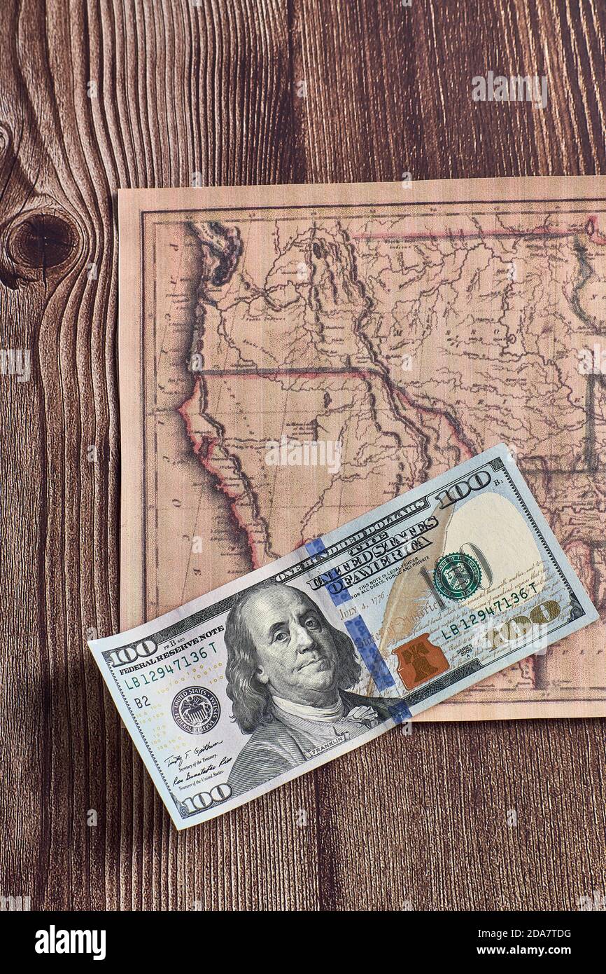 Top view closeup of 100$ banknote placed on an ancient map on a wooden ...