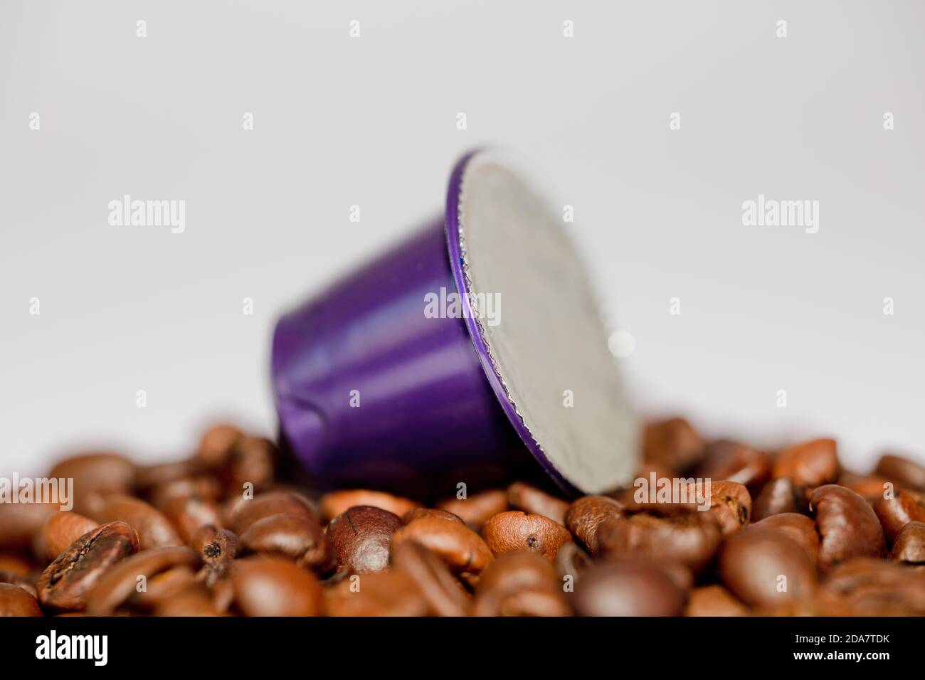 purple coffee capsule, on coffee beans, white background Stock Photo ...