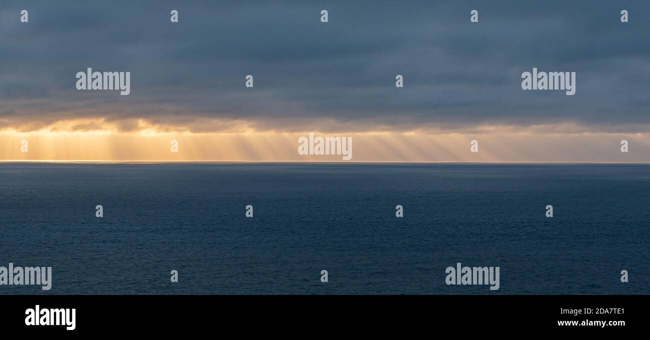 Sun rays coming down from the clouds over the ocean Stock Photo - Alamy