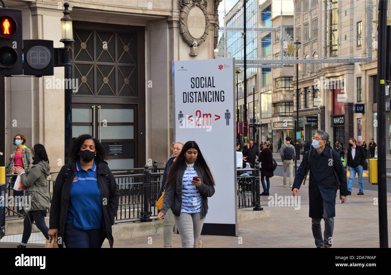 People walk past a Social Distancing sign on Oxford Street, London ...