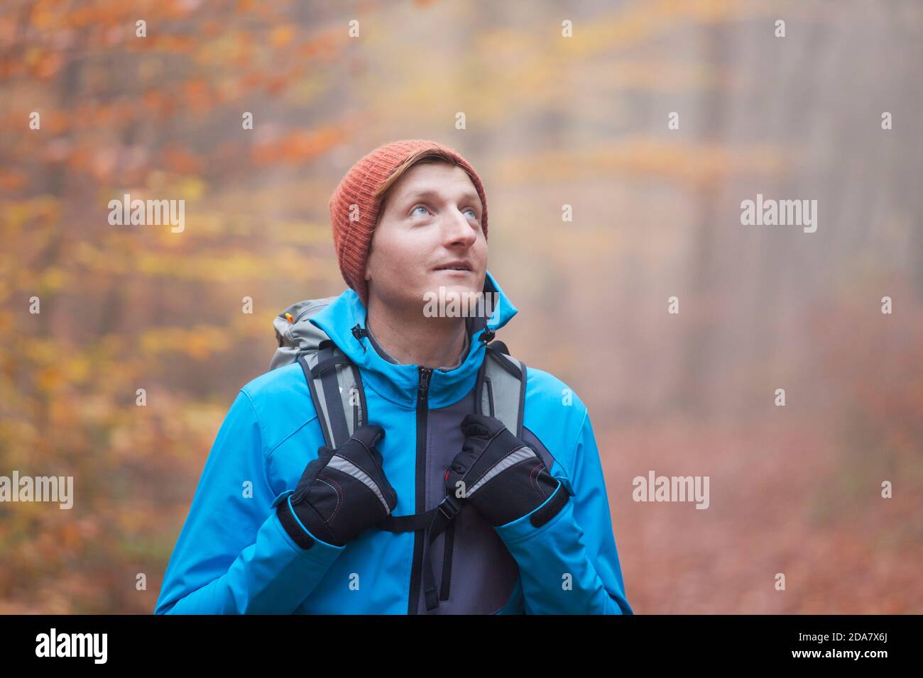 Young man hiking with backpack in a forest in fall - focus on the face ...