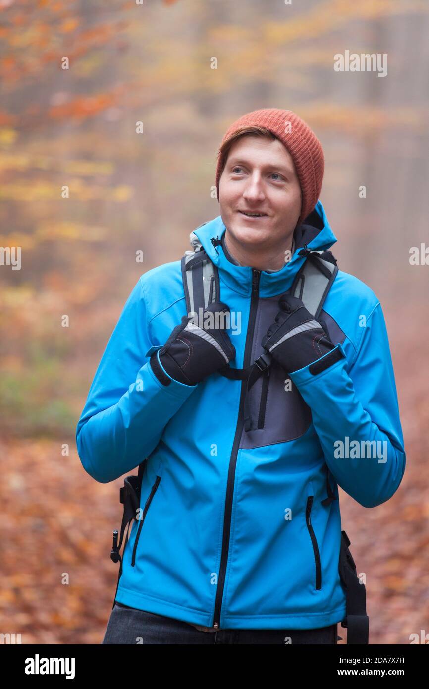 Young man hiking with backpack in a forest in fall - focus on the face ...