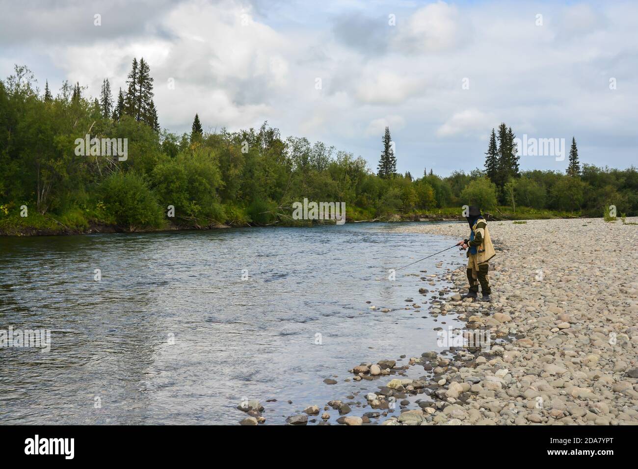 Fisherman on the river. A young man fishes with a spinning rod on the ...