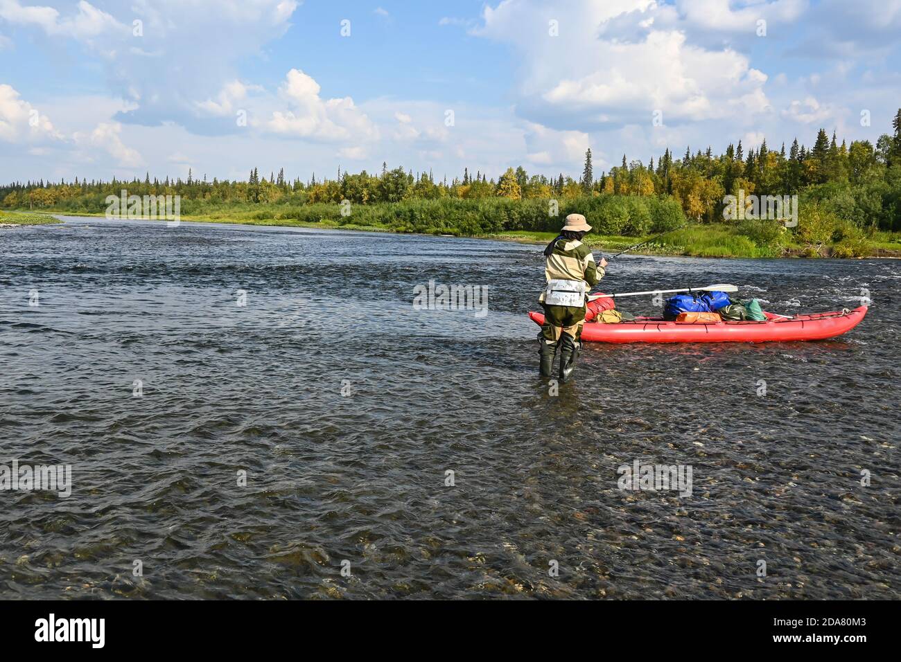 Fisherman on the river. A young man fishes with a spinning rod on the ...
