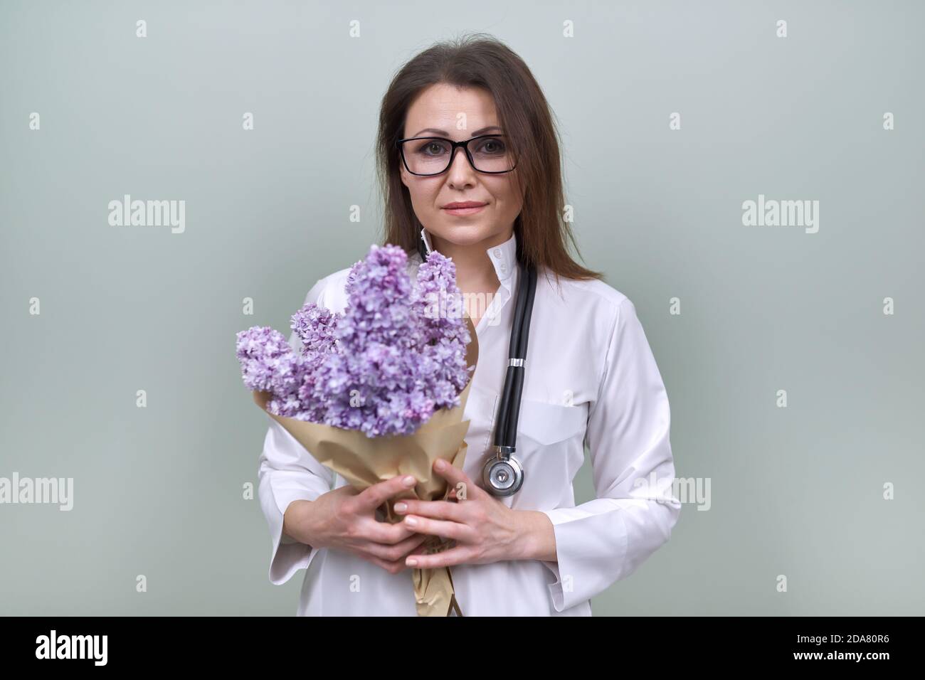 Portrait of female doctor with stethoscope with bouquet of lilac ...