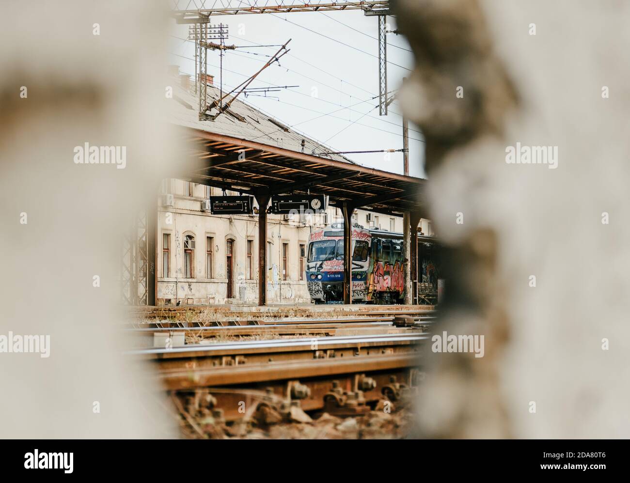 View of a railway station with a train seen through a hole in the wall ...