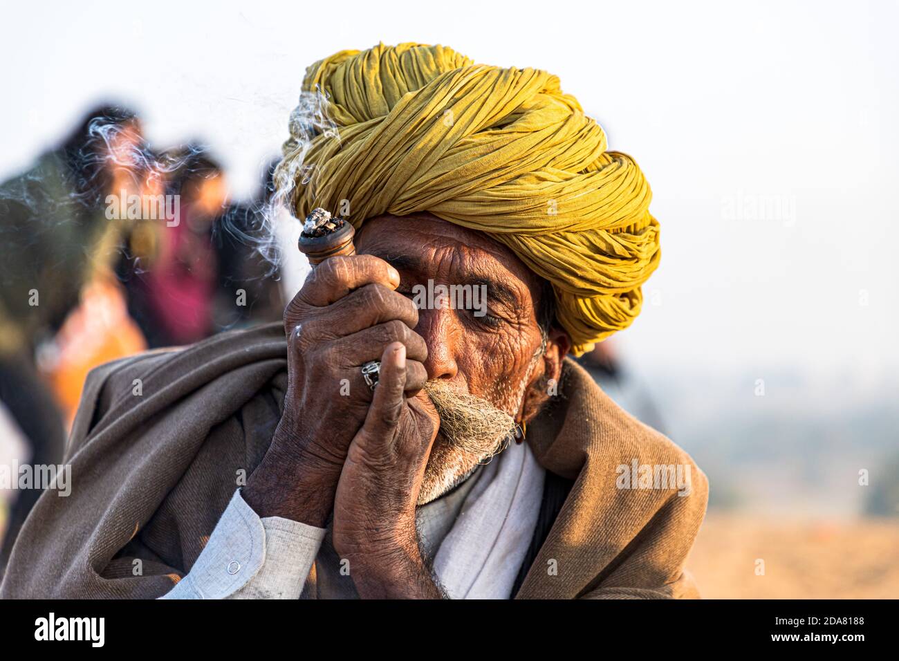 portrait shot of an old tribal man smoking chillam at pushkar camel ...