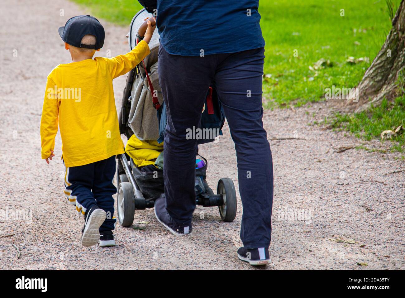 Kid and an adult man walking a baby with a stroller Stock Photo - Alamy