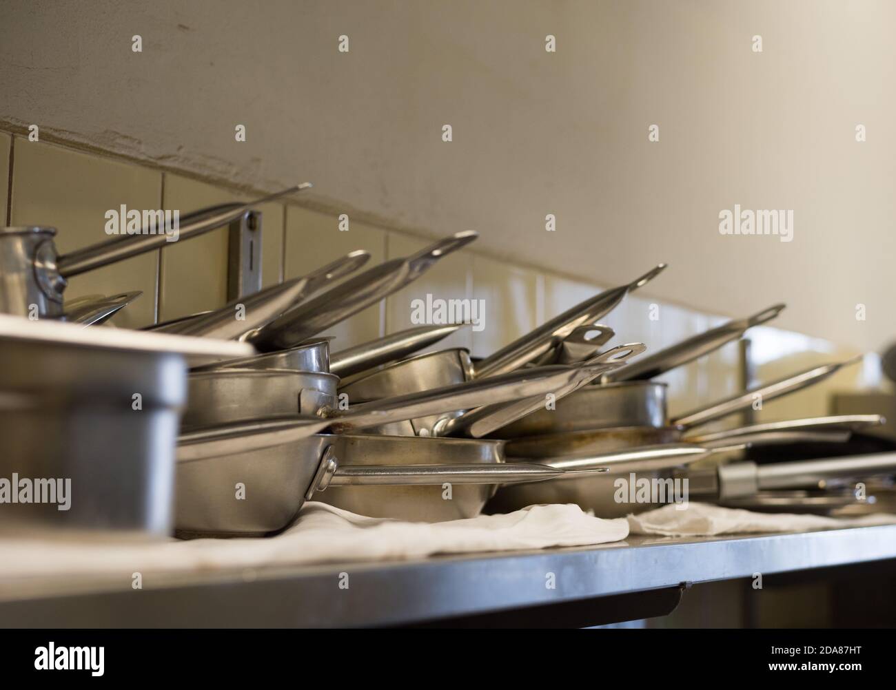 Neatly stacked stainless steel pans and pots standing on shelf in ...