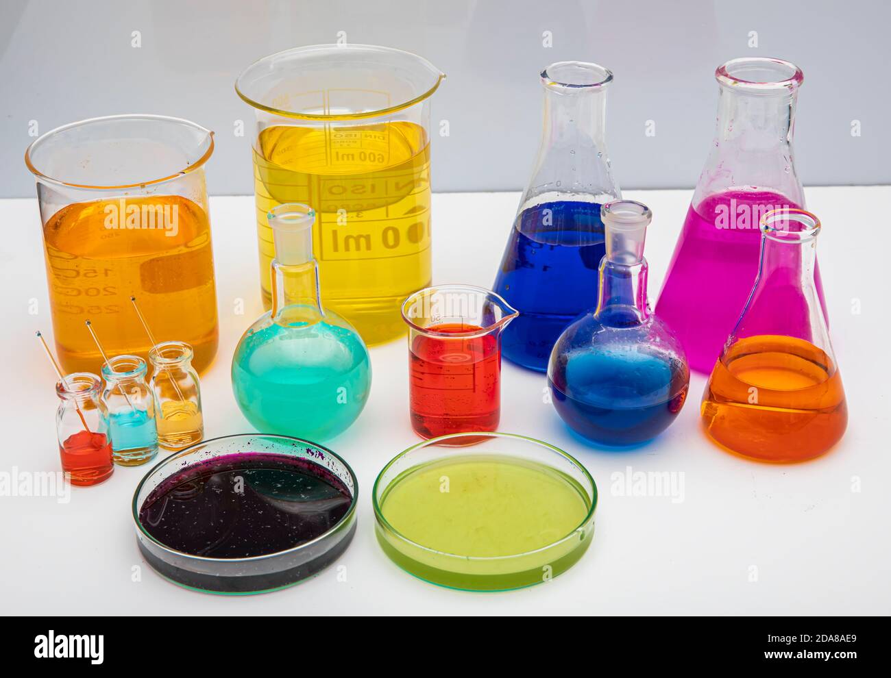 Laboratory glassware with liquids of different colors on white table ...