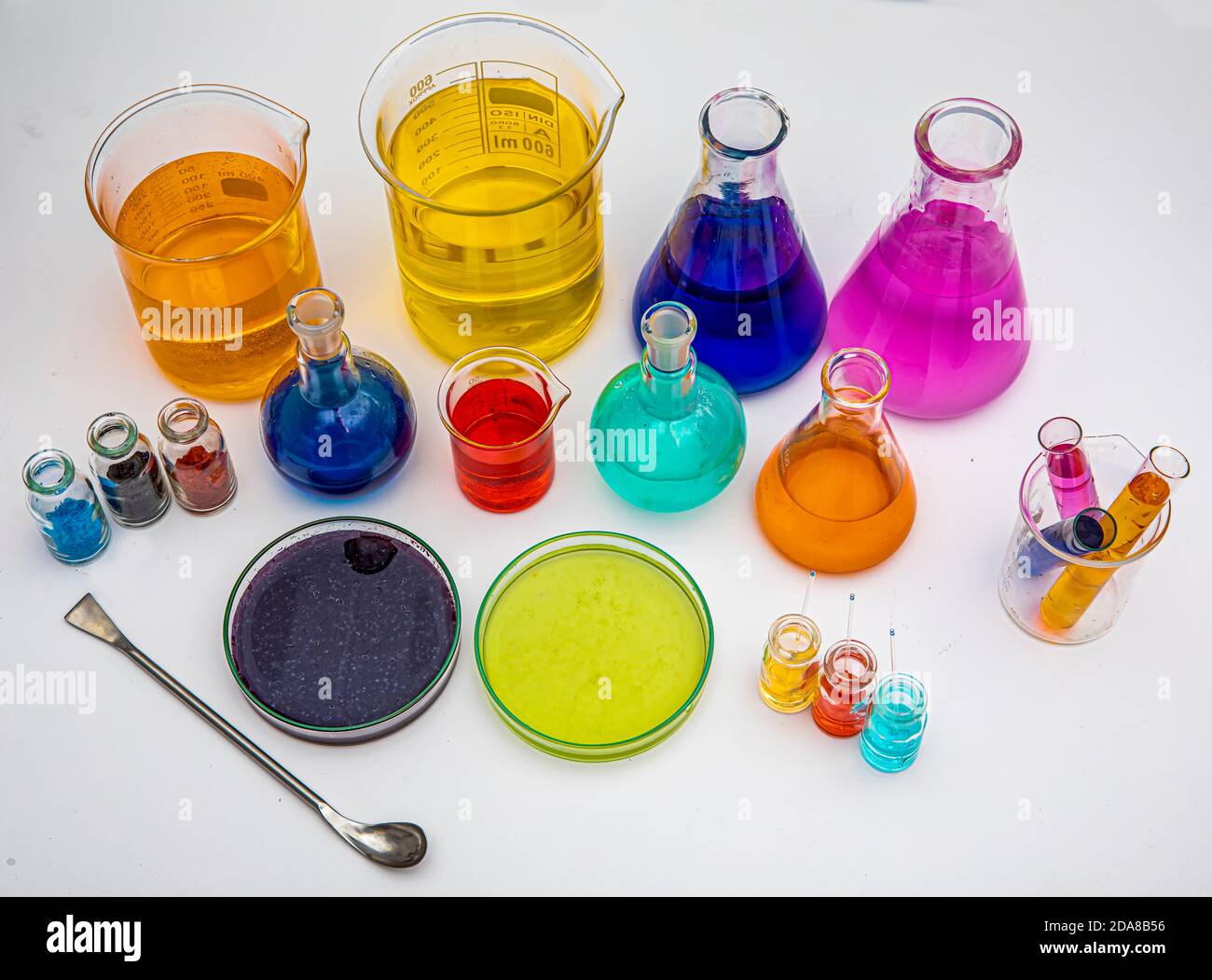 Laboratory glassware with liquids of different colors on white table ...