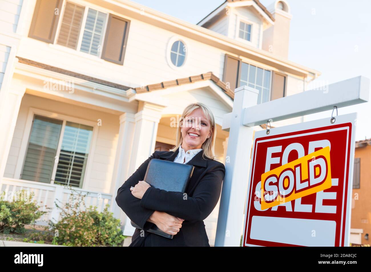Female Real Estate Agent in Front of Sold For Sale Sign and Beautiful ...