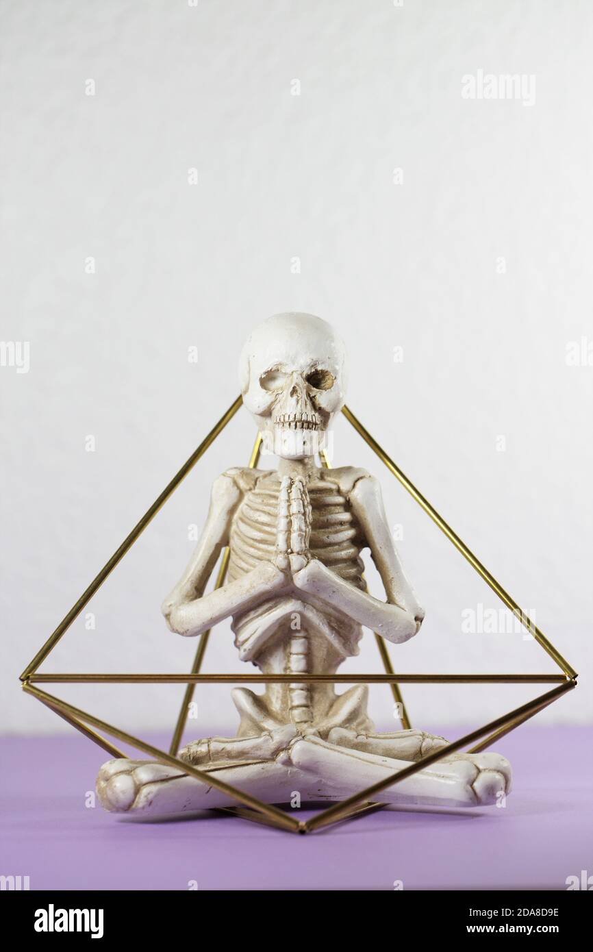 A meditating skeleton figure inside a metal geometric cage Stock Photo ...