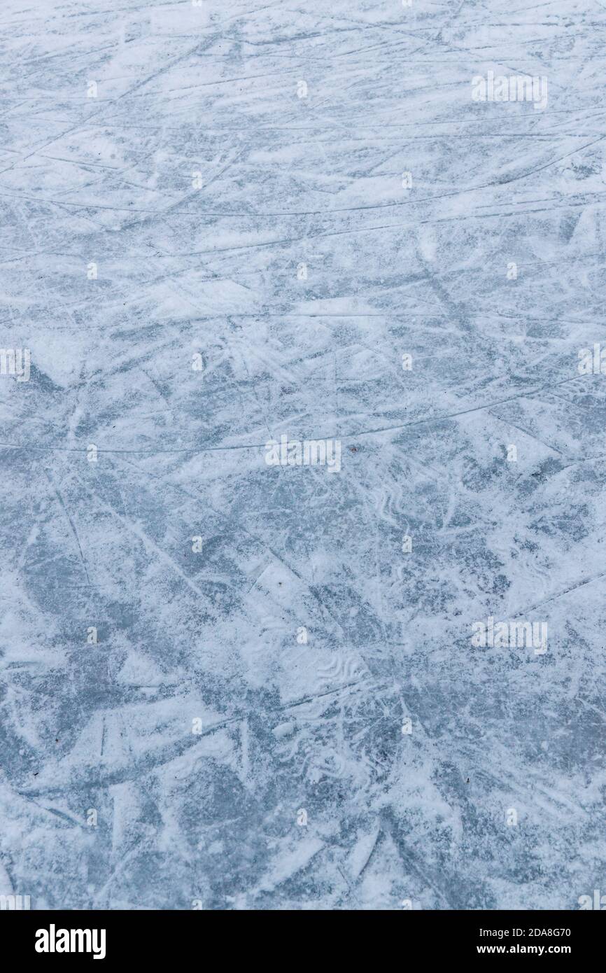 Grey blue ice surface with scratches from ice skating on a public ice ...