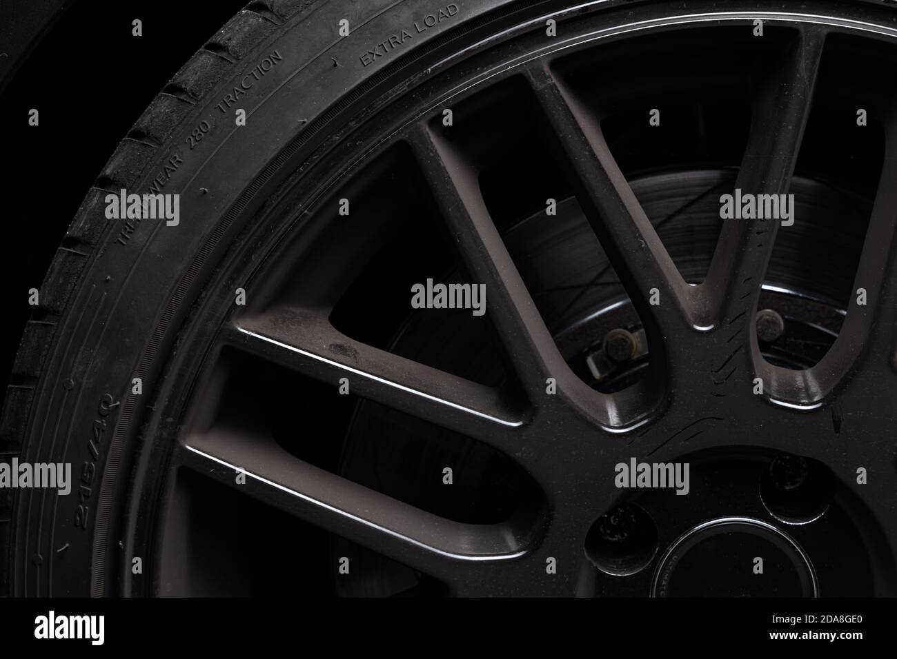 Side view of a black aluminum rim with rubber tire, dirty, dusty, break ...