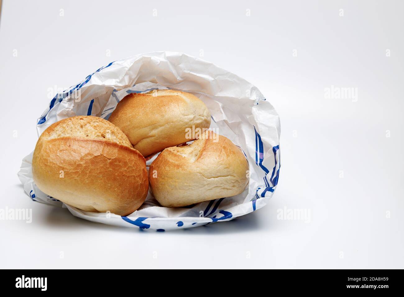 Three wheat buns in a blue and white paper bag on a uniform white ...