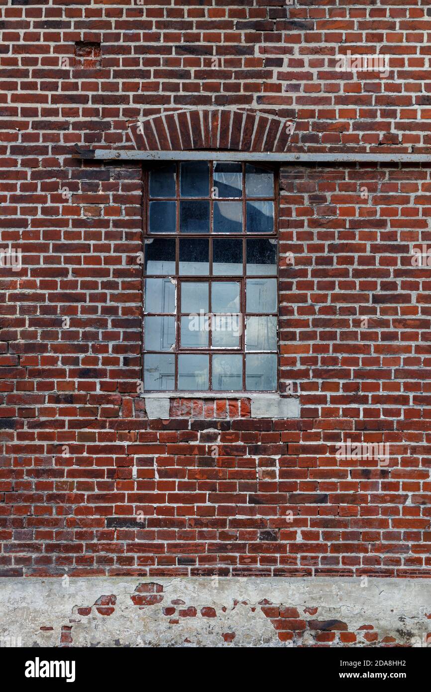 Industrial window with a metal rusted frame on a red damaged brick wall ...