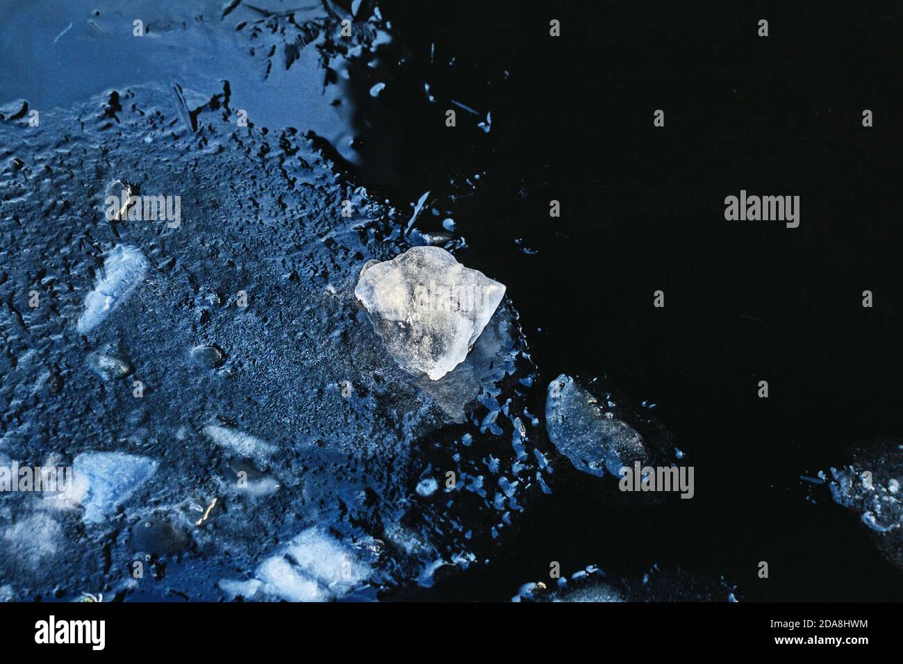 Pretty white ice on dark ice in deep dark water Stock Photo - Alamy