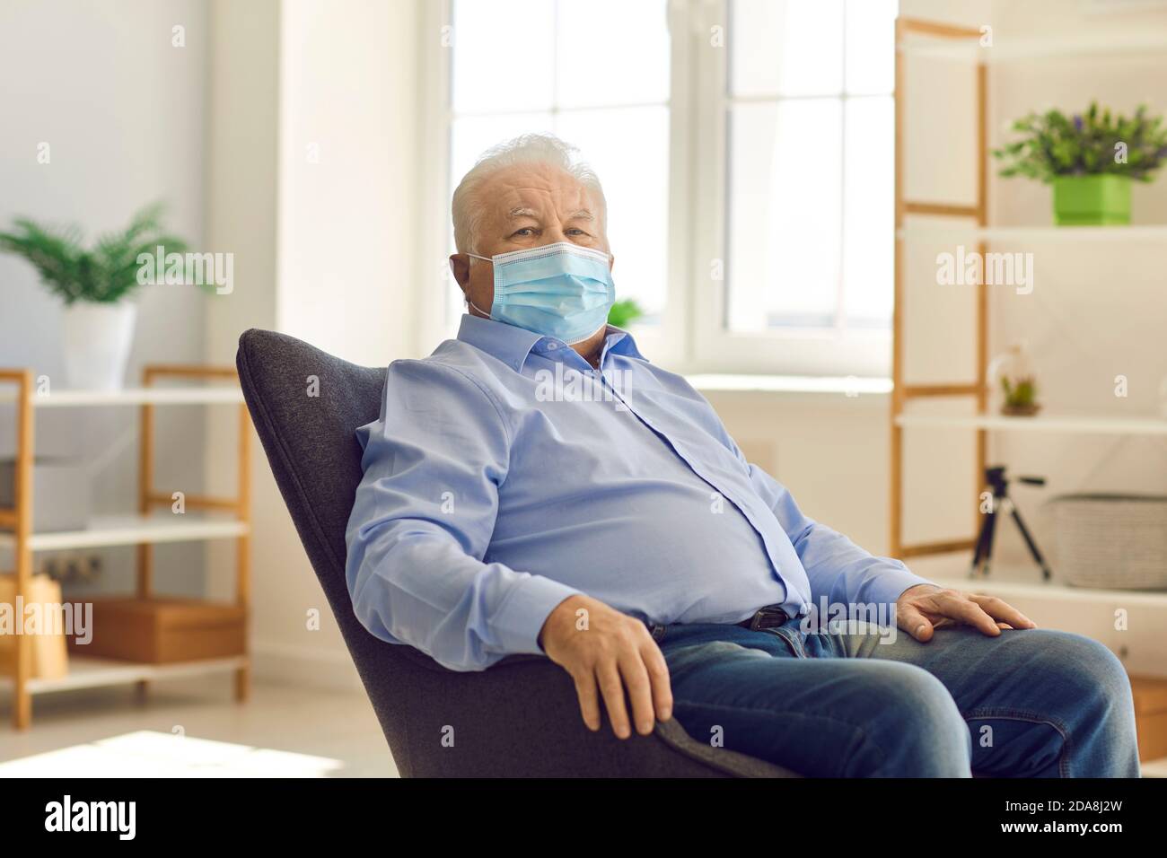 Serious senior citizen wearing medical face mask looking at camera ...