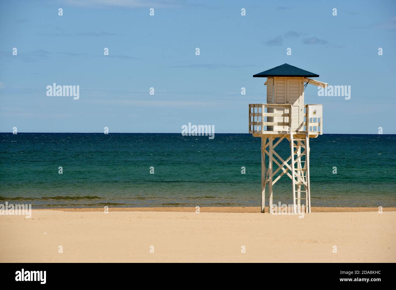 A watchtower on an empty beach looks out over a perfectly calm ...