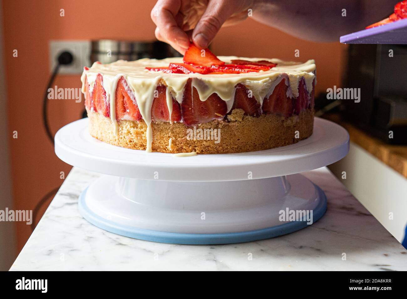 Homemade cake with hand placing strawberry slice on top. Close up Stock ...