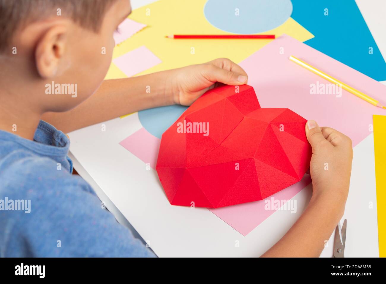 Boy making red polygonal paper heart. Education, learning, paper craft ...