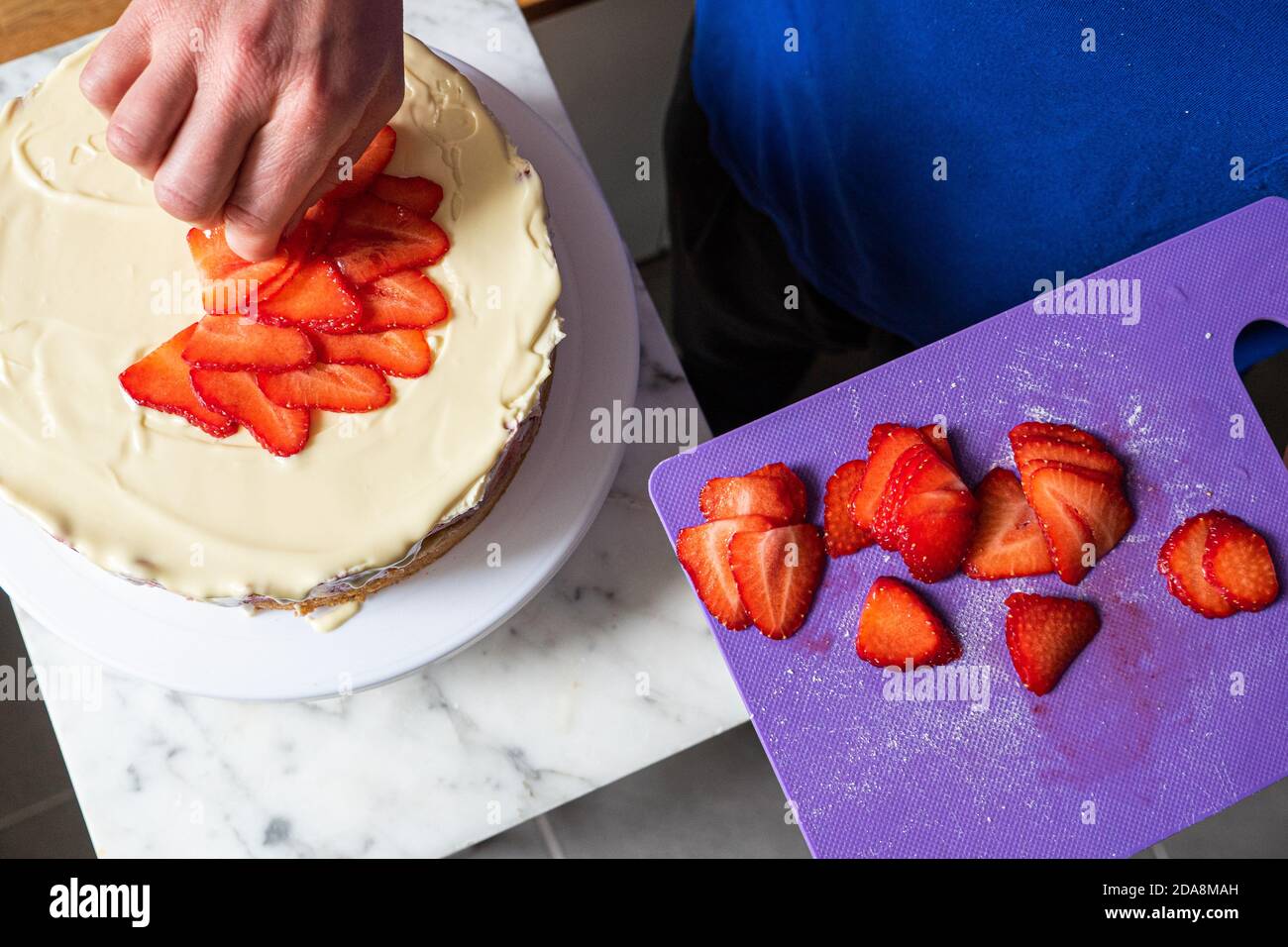Homemade cake preparation with hand arranging strawberry slices ...