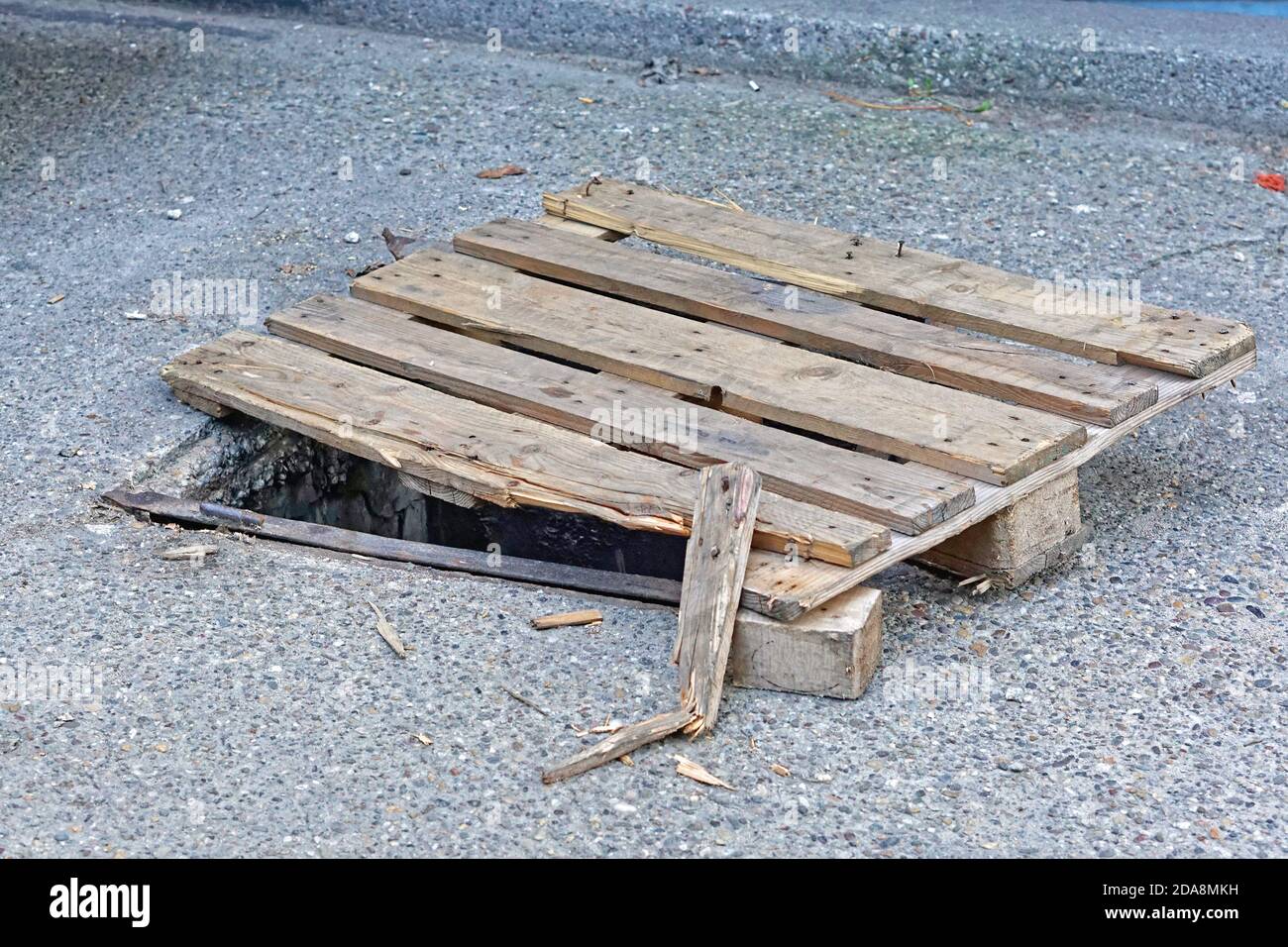 Broken cargo pallet at open manhole shaft Stock Photo - Alamy