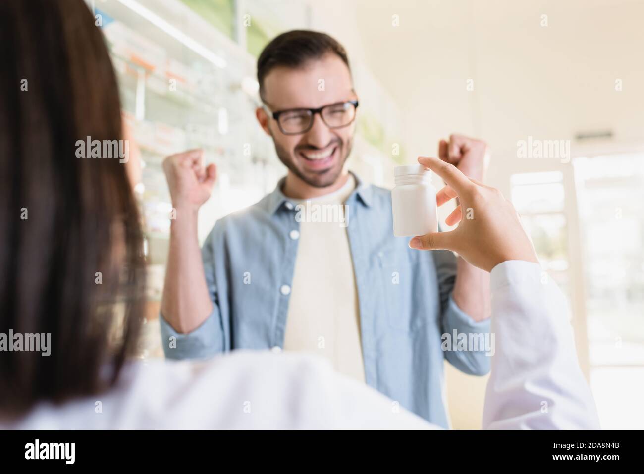 excited customer looking at pharmacist holding bottle with medication ...