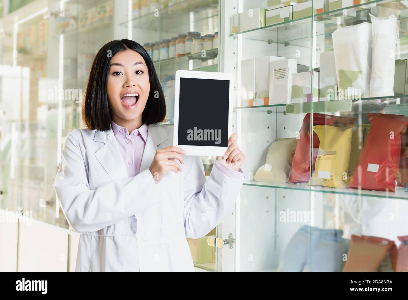 excited asian pharmacist in white coat holding digital tablet with ...