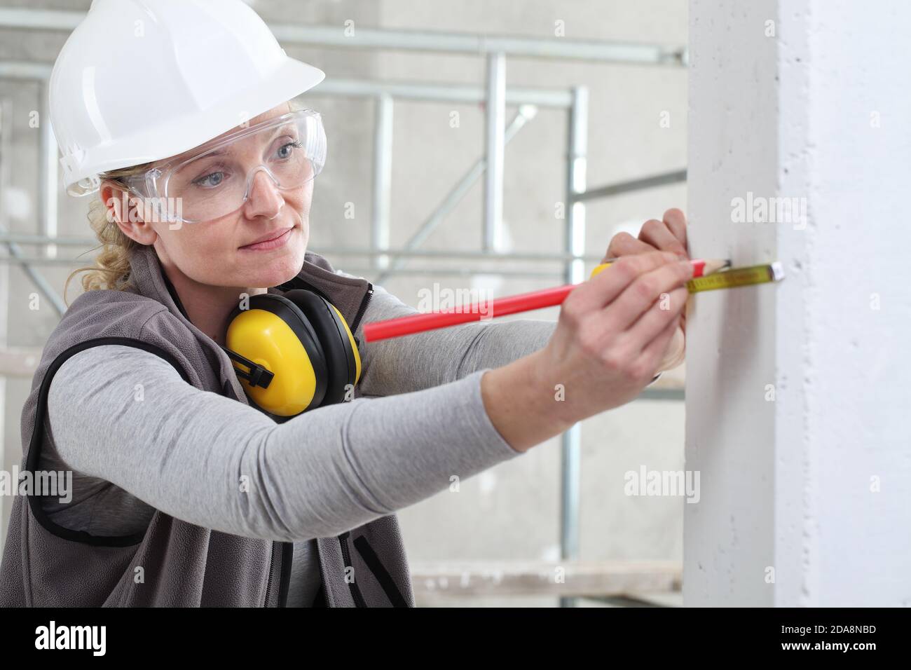 woman construction worker work with meter tape and pencil, measure wall ...