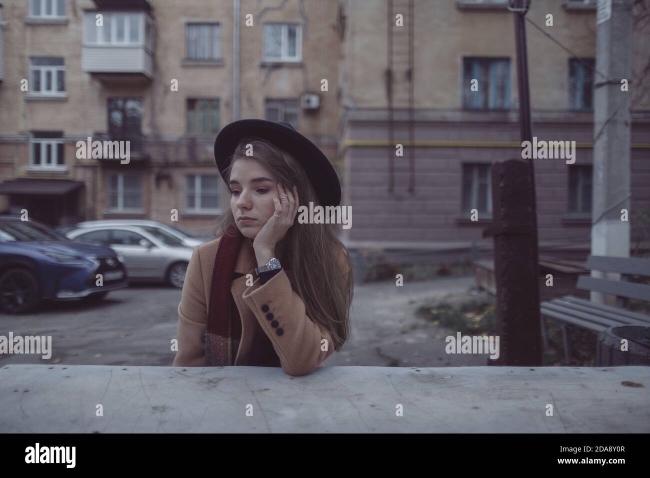 sad Ukrainian young girl sitting on a bench in the yard of his ...
