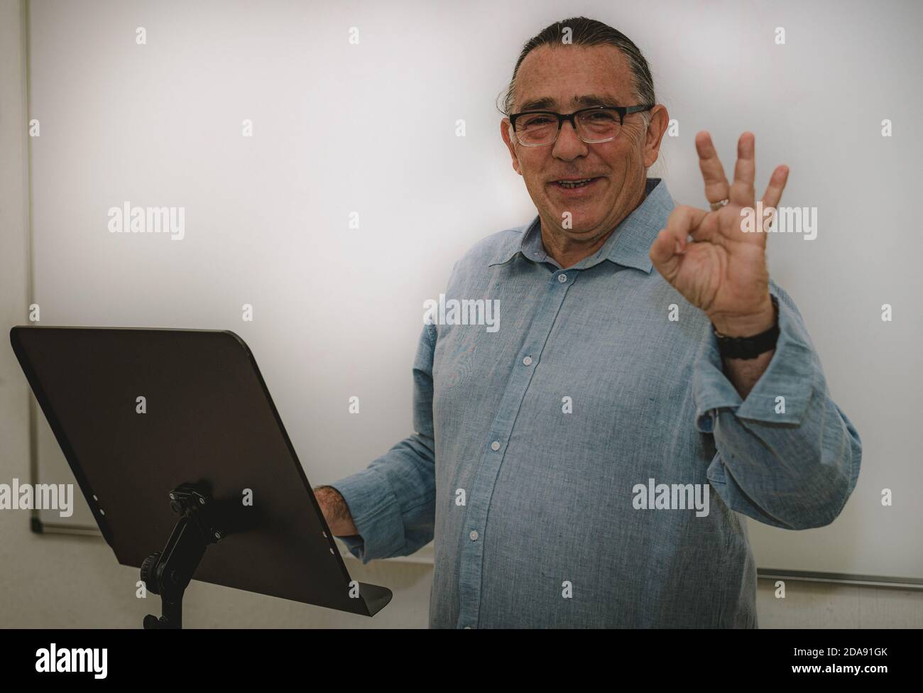 an adult man with glasses makes a presentation at a lectern and raising ...