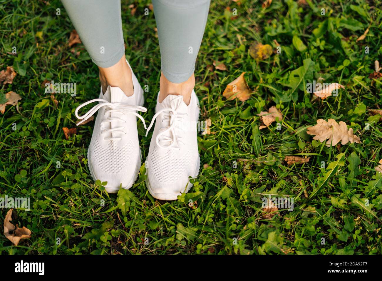 Close-up of woman feet in white sneakers standing and poses in place on ...