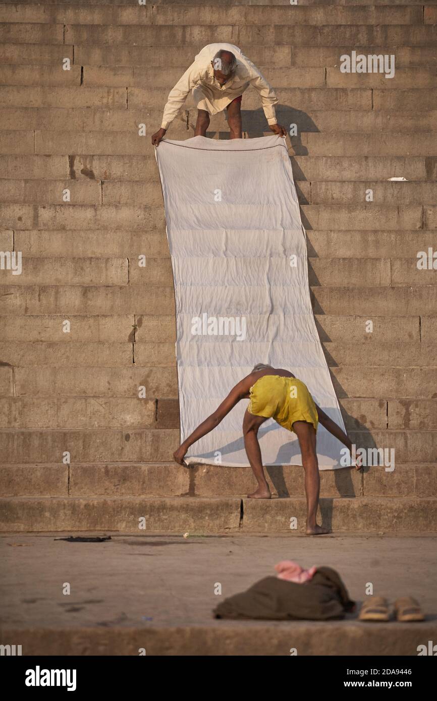 Varanasi, India, January 2008. Two people drying a sheet on the stairs ...