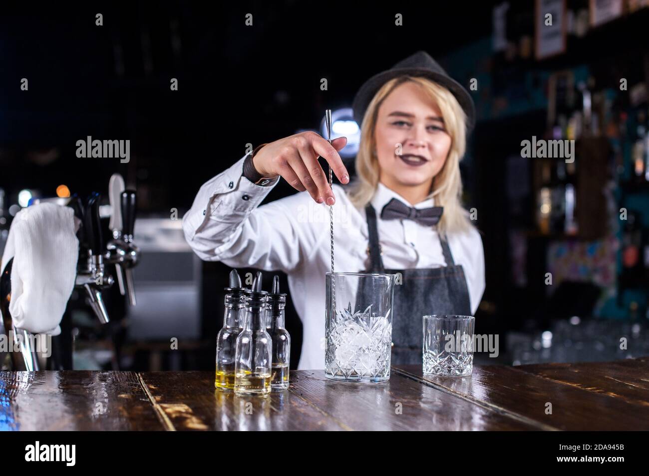 Charming girl bartender makes a show creating a cocktail behind bar ...