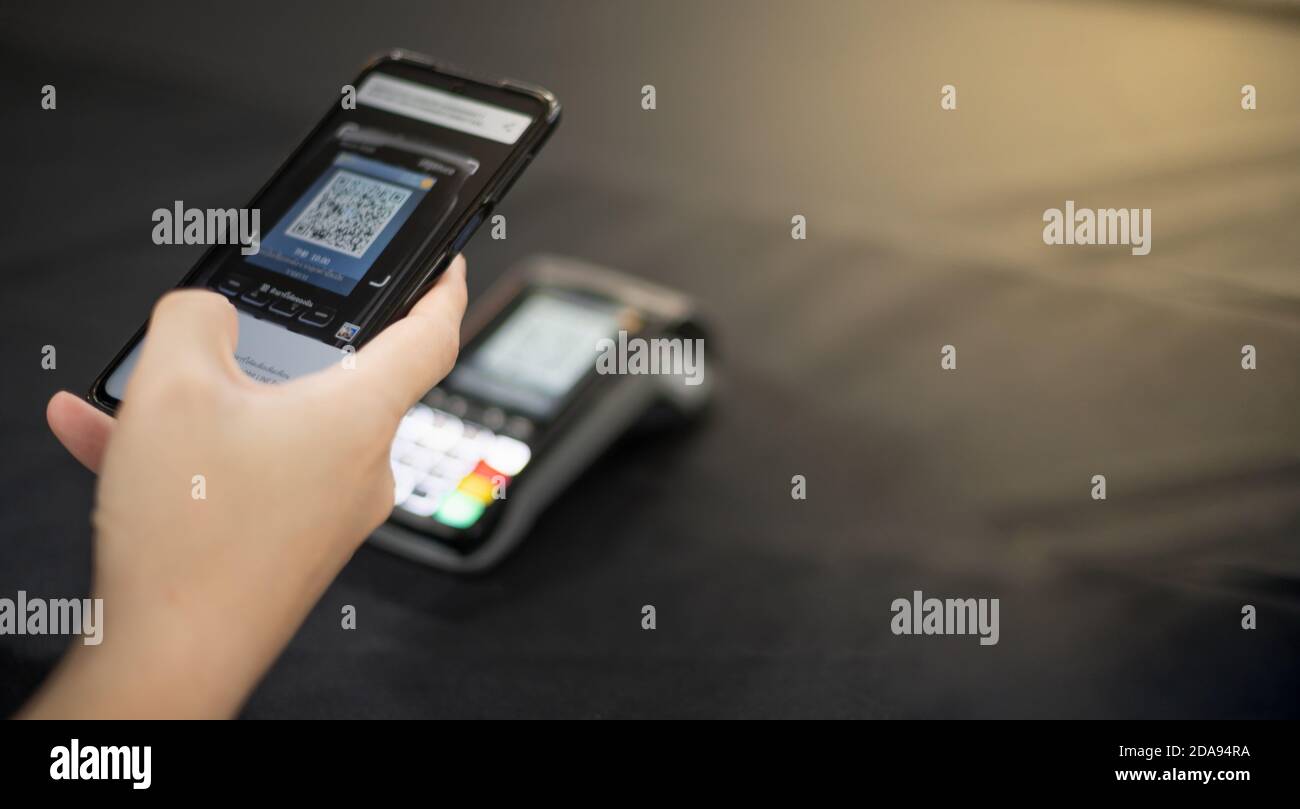 Female hand scanning the QR code with mobile phone for pay at the shop ...