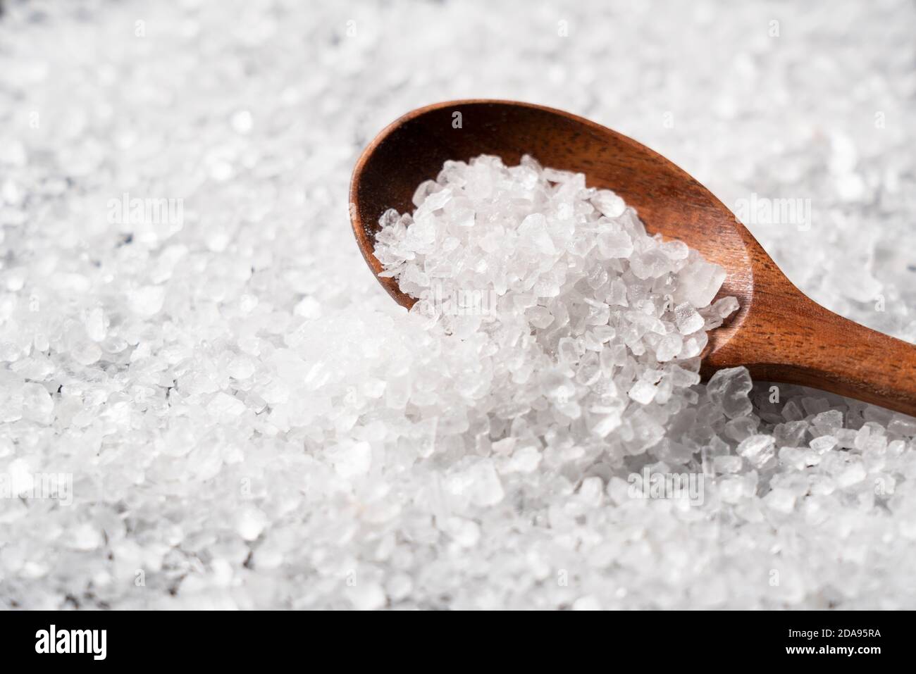 Himalayan rock salt and wooden spoons laid across the screen. Close-up ...