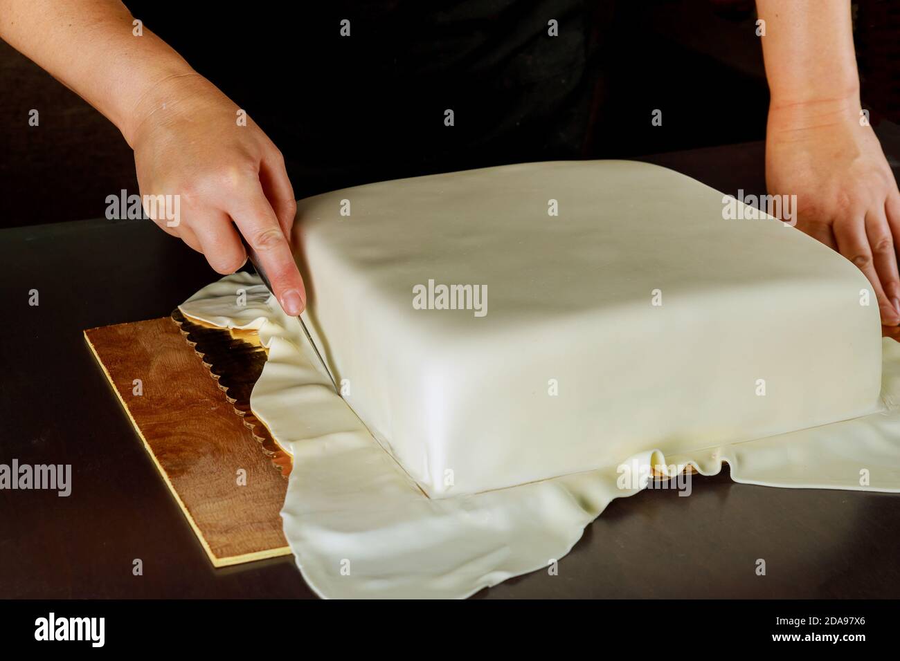 Woman in bakery covering wedding cake with white fondant Stock Photo ...