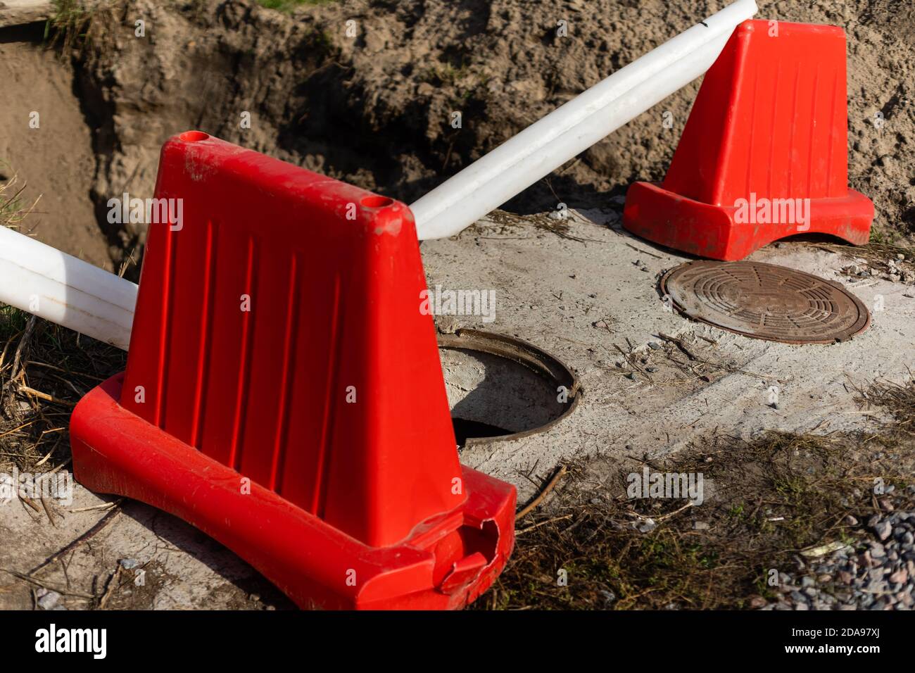 Dangerous open hatch without cover and a warning fence on the road ...