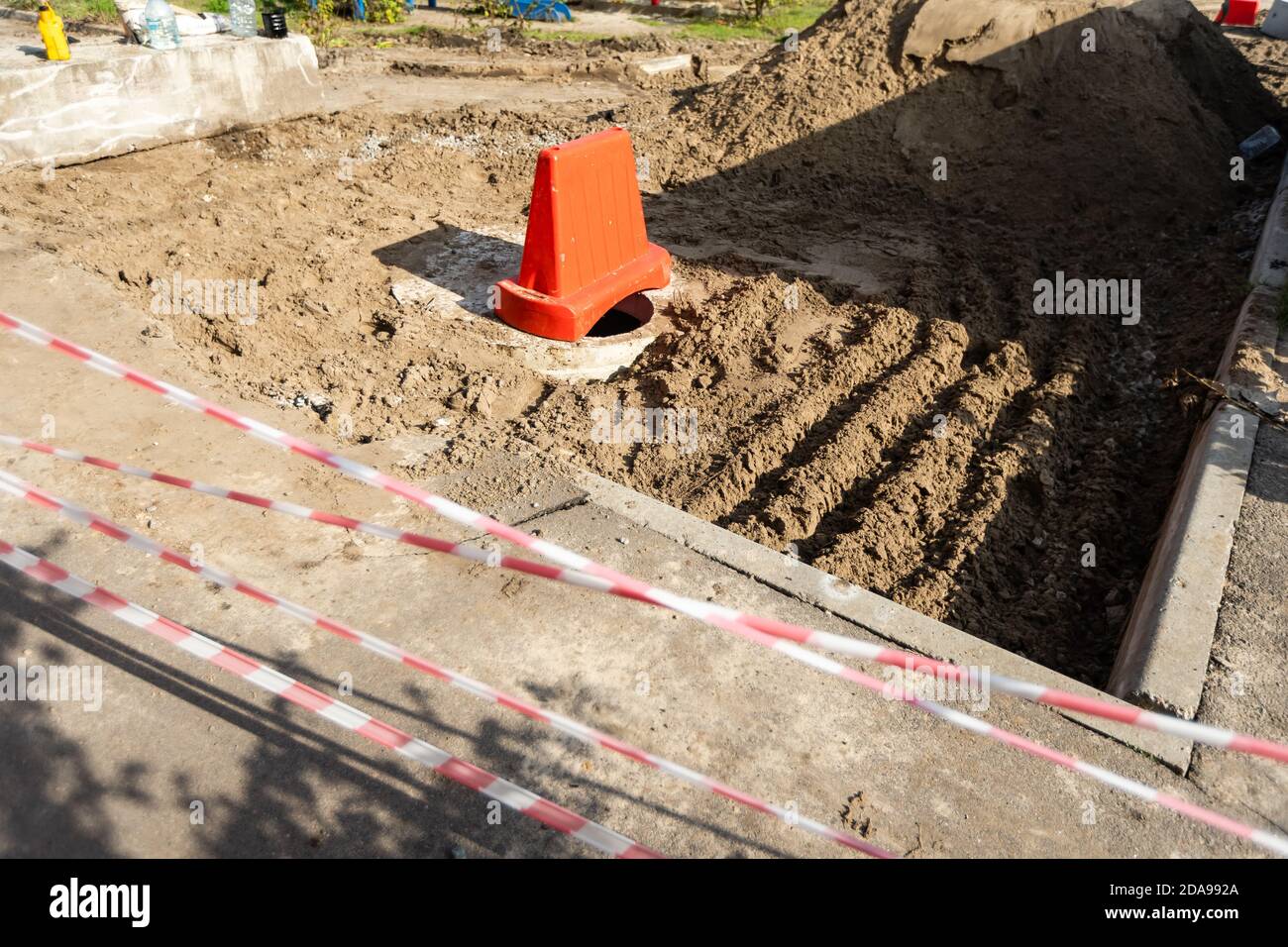 Dangerous open hatch without cover and a warning fence on the road ...