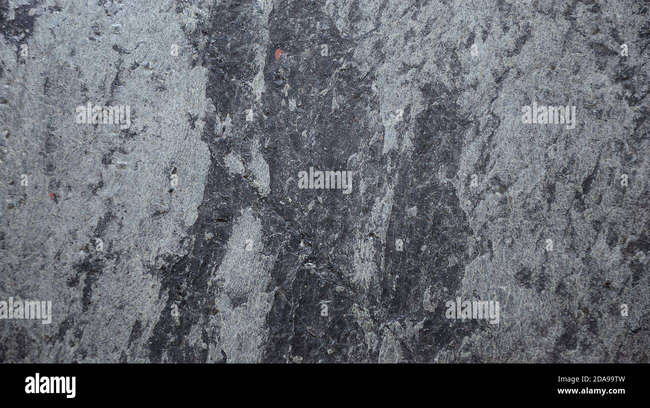 The flat surface of a roughly worked black natural stone with veins of ...